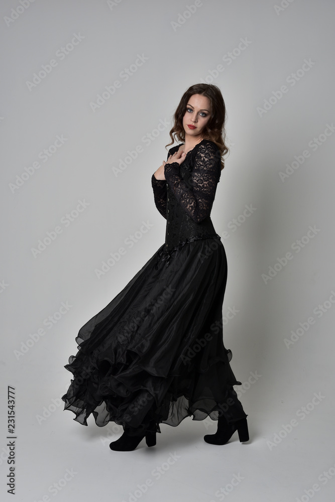 Full Length Portrait Of Brunette Girl Wearing Long Black Gown With