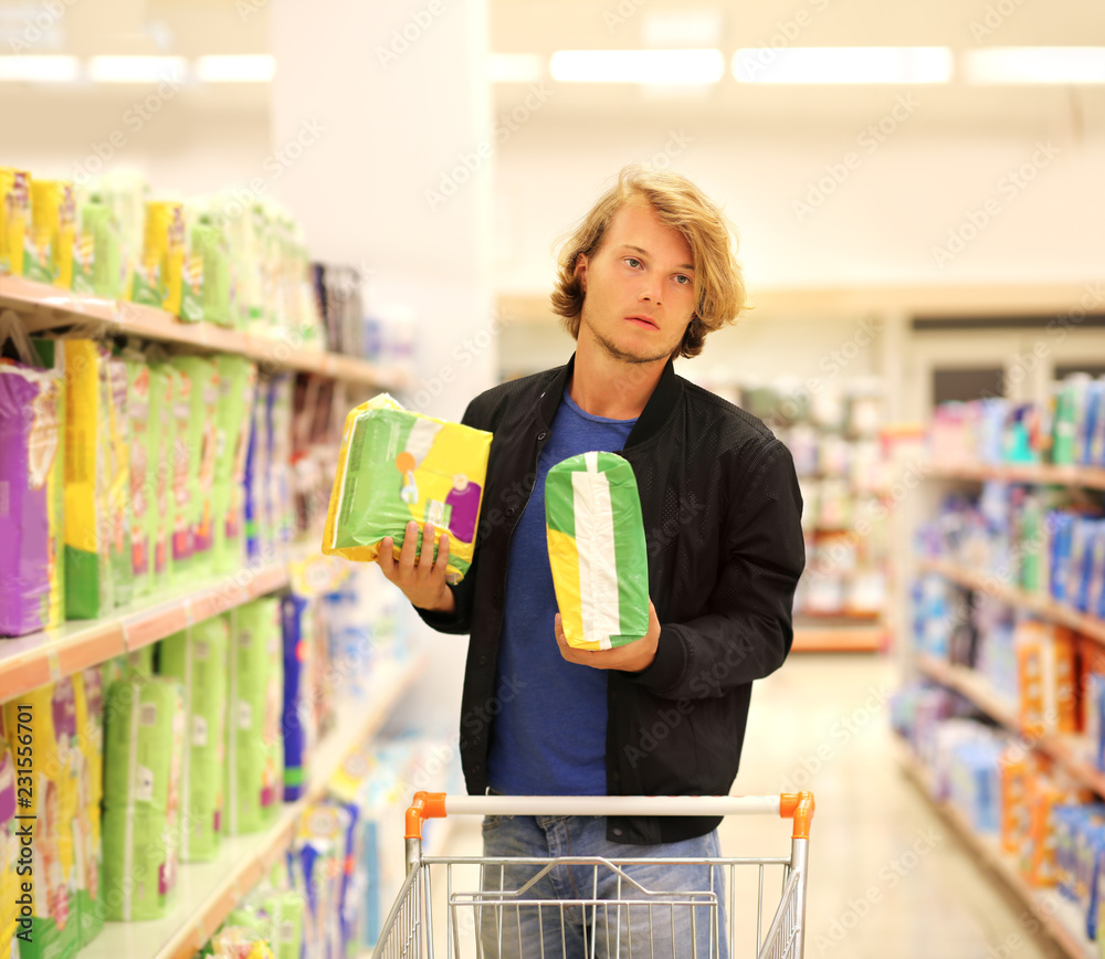 Man shopping in supermarket reading product information Stock Photo ...