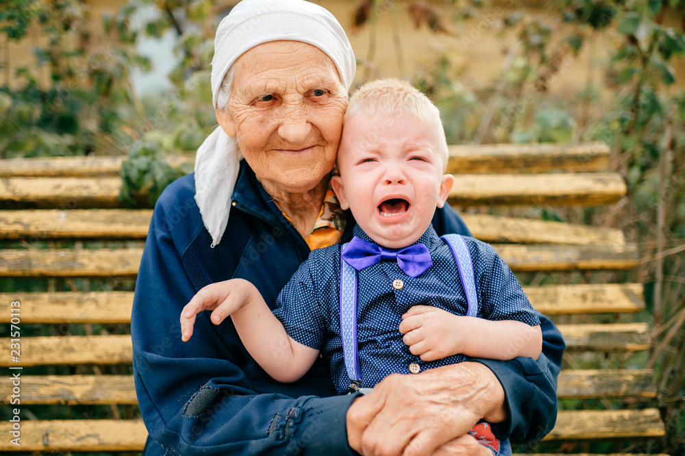 Happy cheerful great grandmother sitting with great grandson outdoor ...