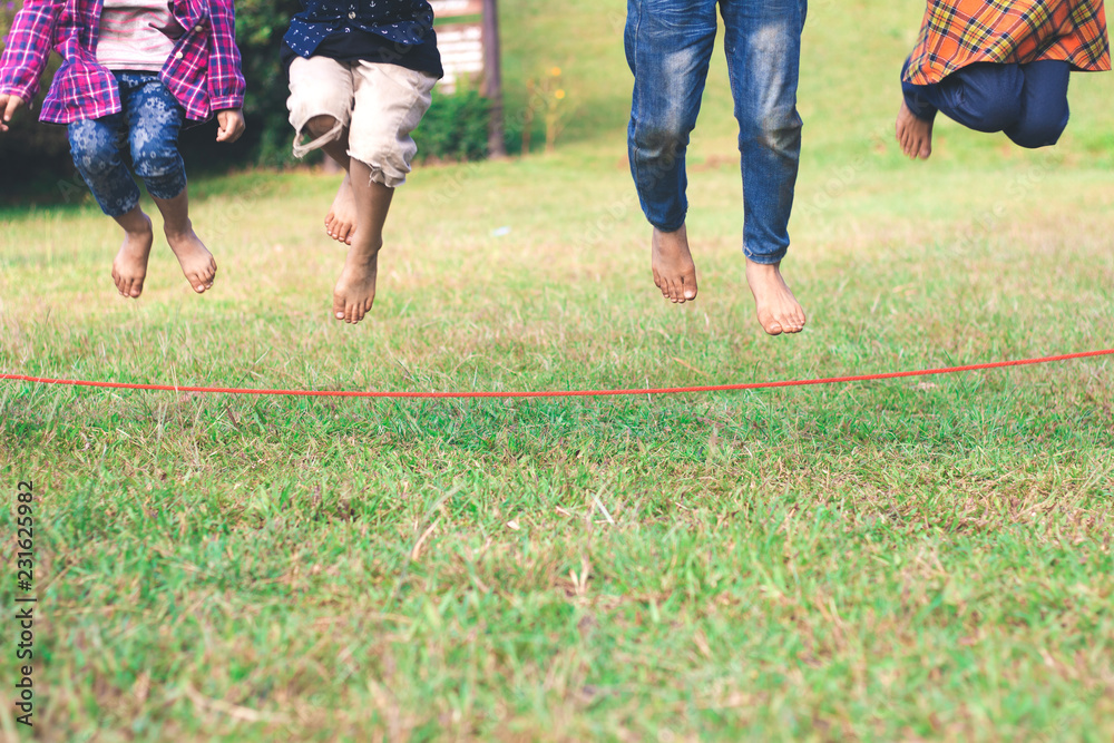 Four children jumping over the rope in park Stock Photo | Adobe Stock