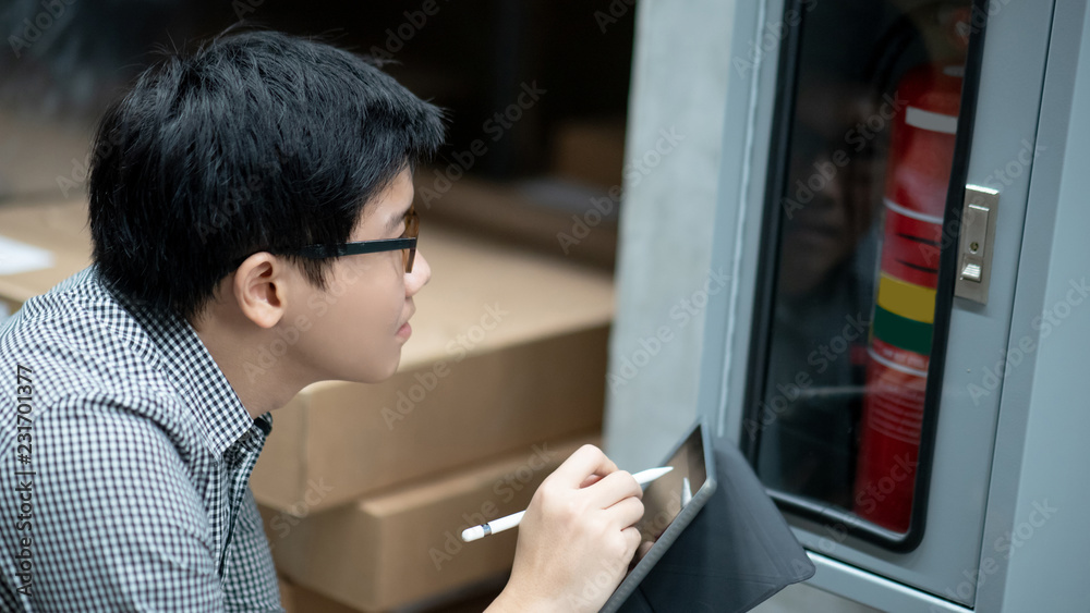 Young Asian male technician checking red fire extinguisher in fire hose ...