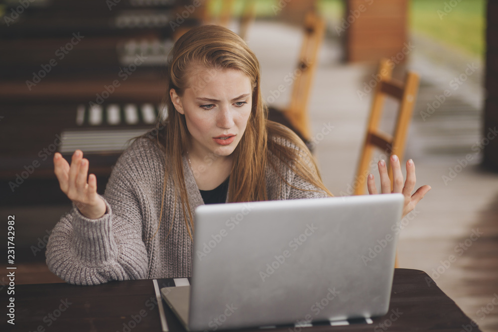 Frustrated worried young woman looks at laptop upset by bad news ...