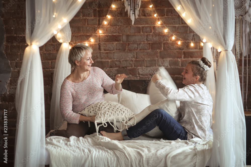 Teen girl plays with mom on bed, fighting pillows Stock Photo | Adobe Stock