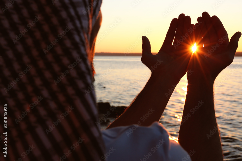 Young Muslim man praying near river at sunset Stock Photo | Adobe Stock