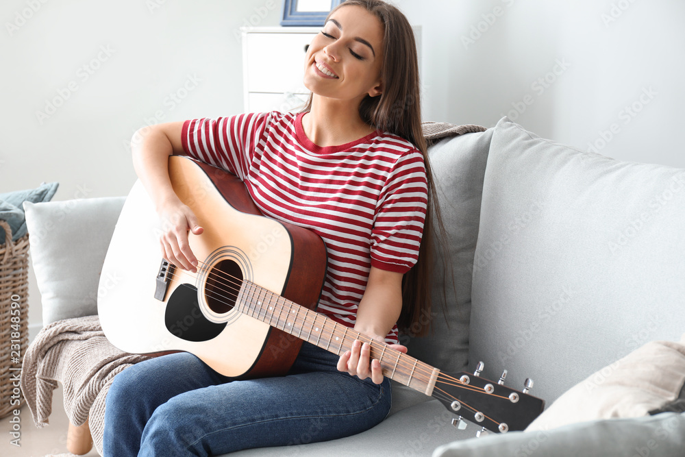 Beautiful woman playing guitar at home Stock Photo | Adobe Stock