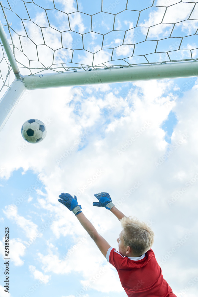 Back view portrait of teenage boy jumping and catching ball while ...