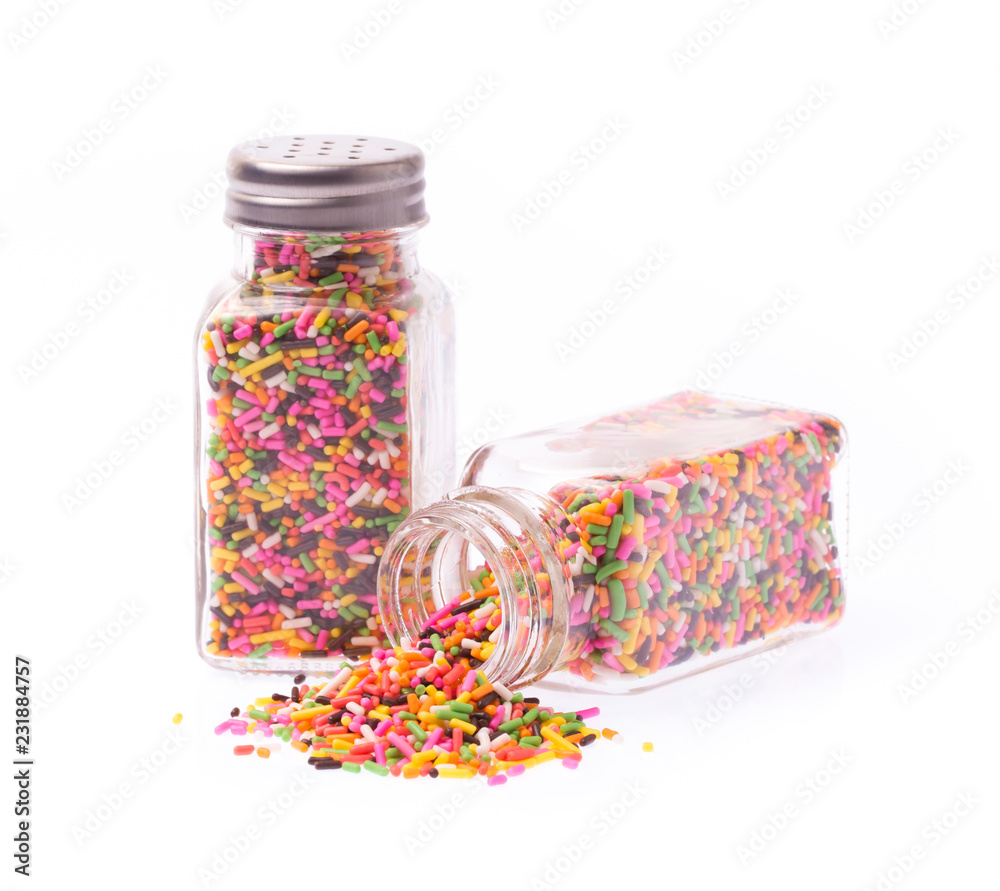 Color sprinkles sugar spilling out of a glass bottle isolated on white ...