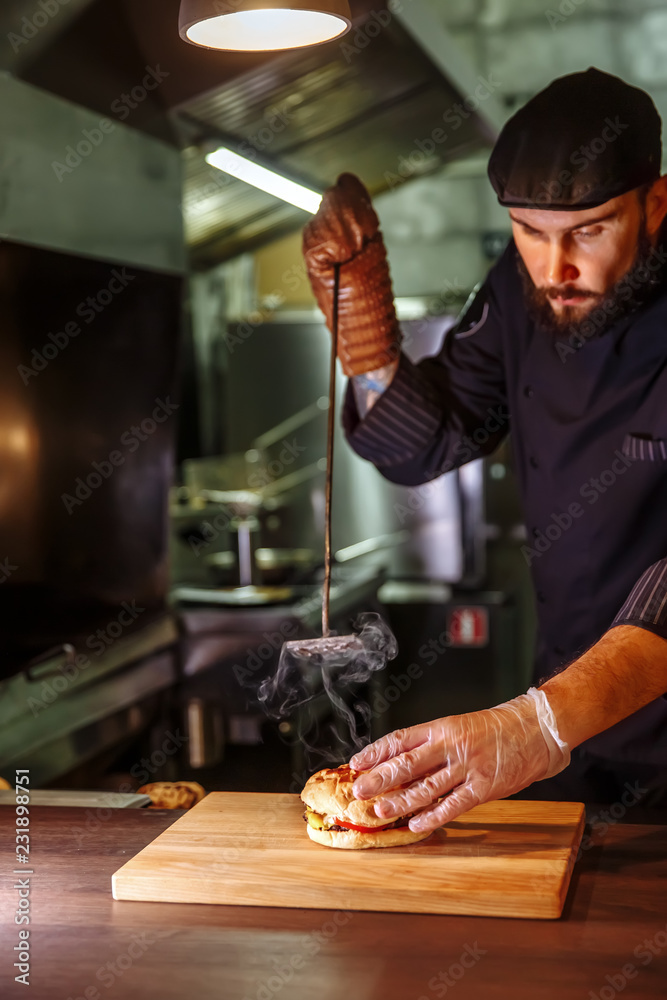 Chef putting bun on top,he making a beef burger for customer order ...