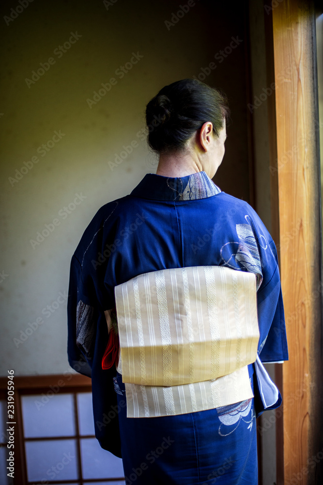 Rear View Of Japanese Woman Wearing Traditional Bright Blue Kimono With