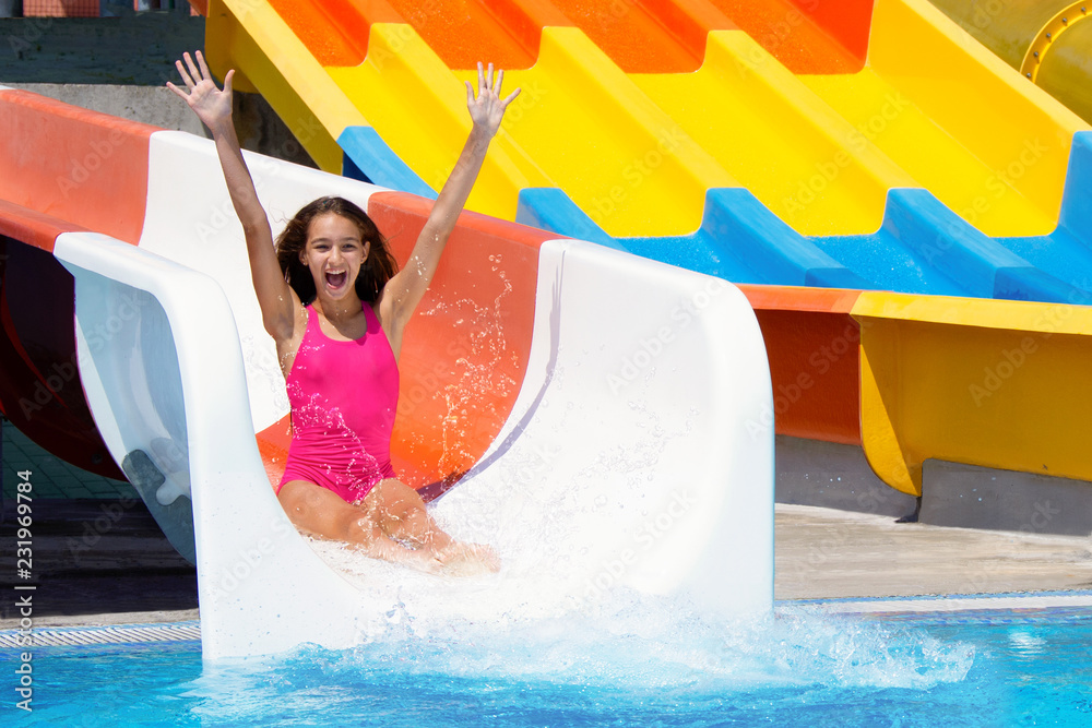Joyful teenage girl going down on water slide make the water splashing ...