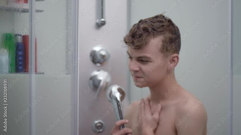 Smiling young boy bathing under a shower at home. Beautiful teen boy ...
