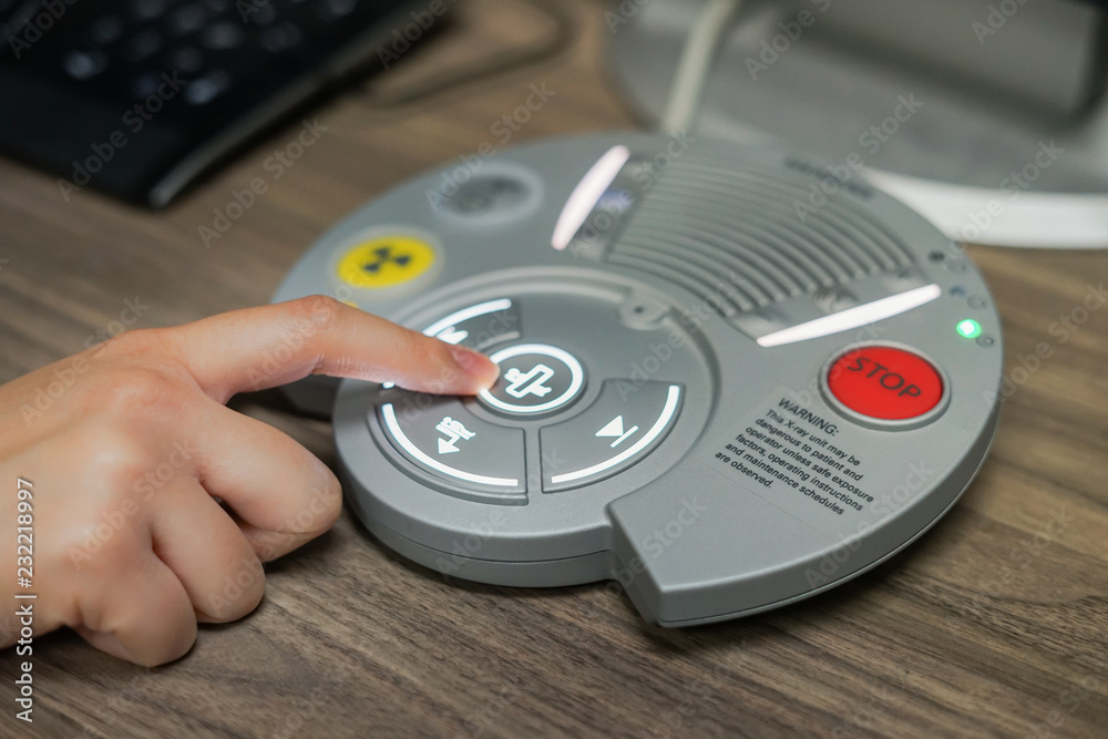 Female hand pressing movement sign button on CT scan control panel ...