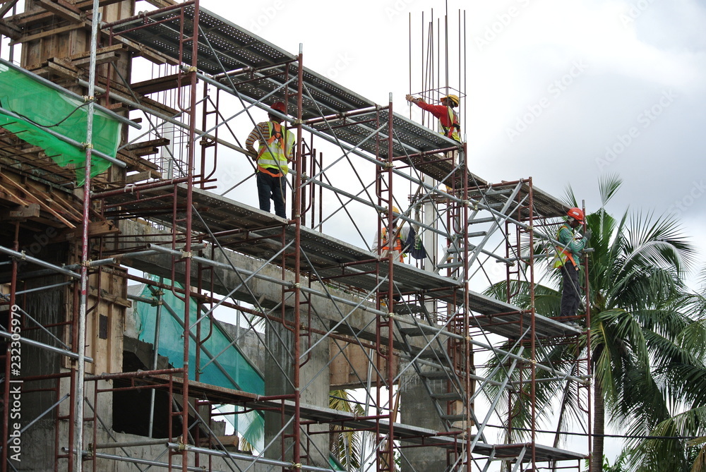 Construction workers wearing safety harness and installing scaffolding ...