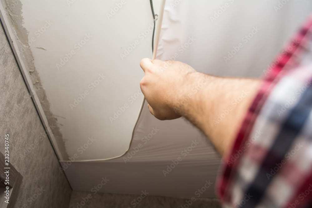repairmen install stretch ceiling made of pvc vinyl film using a gas ...