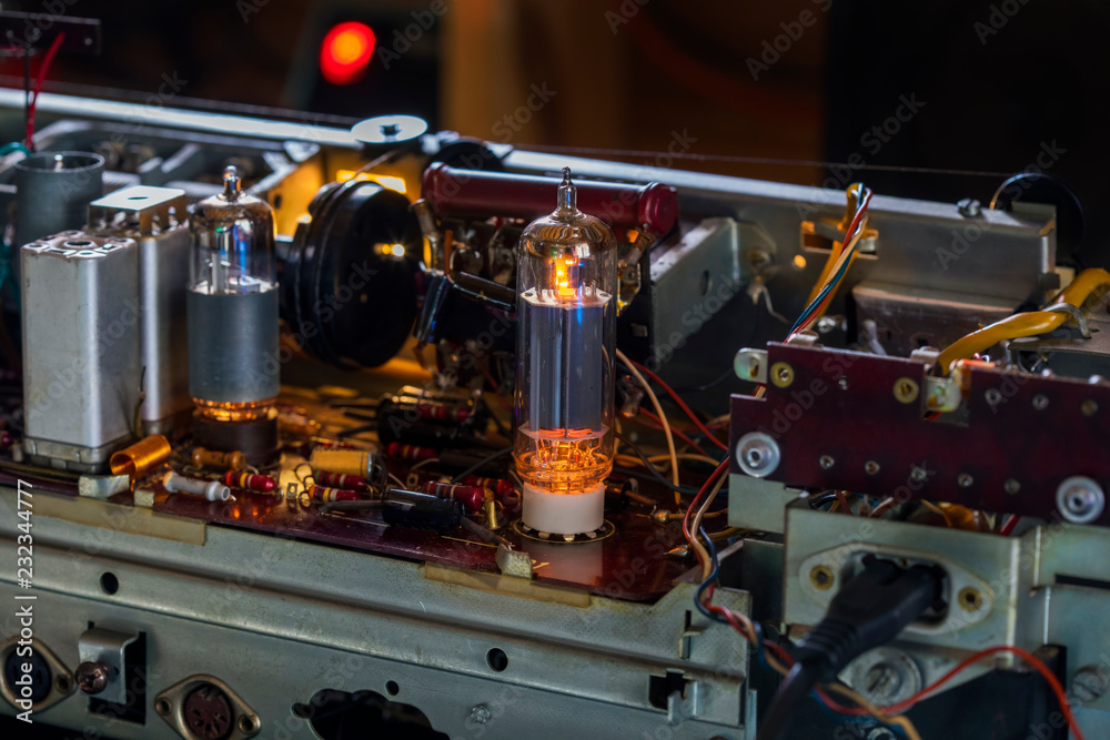 Opened chassis of a tube radio highlighted by the glow of the tubes ...