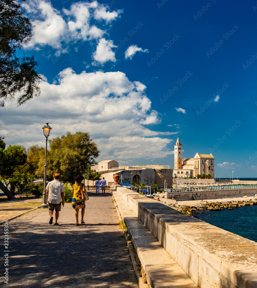 Two lovers walk, holding hands, in the municipal park of Trani, with ...