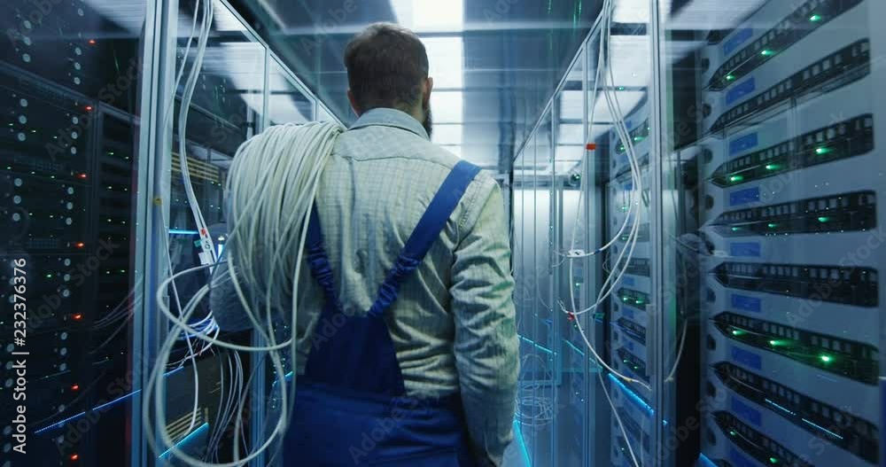 Wide movement stabilized shot of two people working in a data center ...