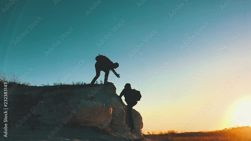 Silhouette of helping hand between two climber. two hikers on top of ...