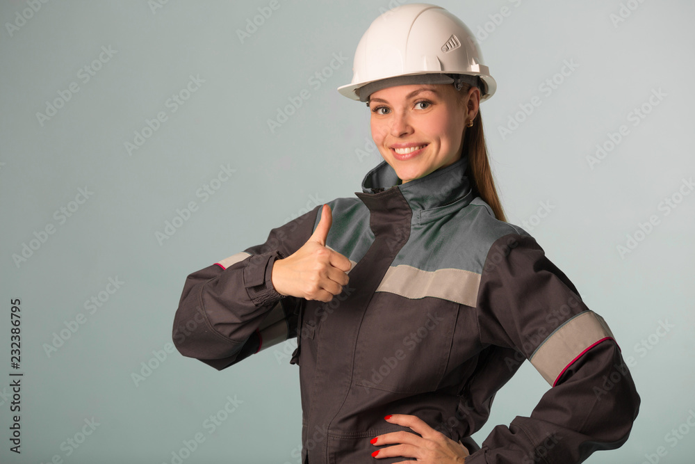 beautiful young girl in working clothes with a helmet on her head on a ...