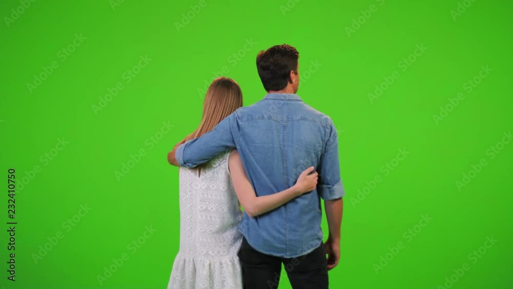 An in-love couple is looking to the horizon, smiling and hugging, over ...