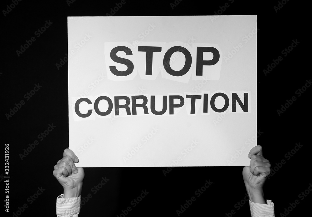 Woman holding placard with text STOP CORRUPTION on dark background ...