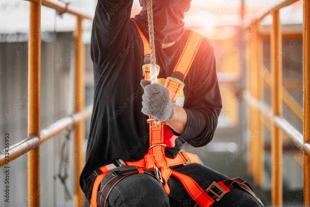Construction worker wearing safety harness and safety line working high ...