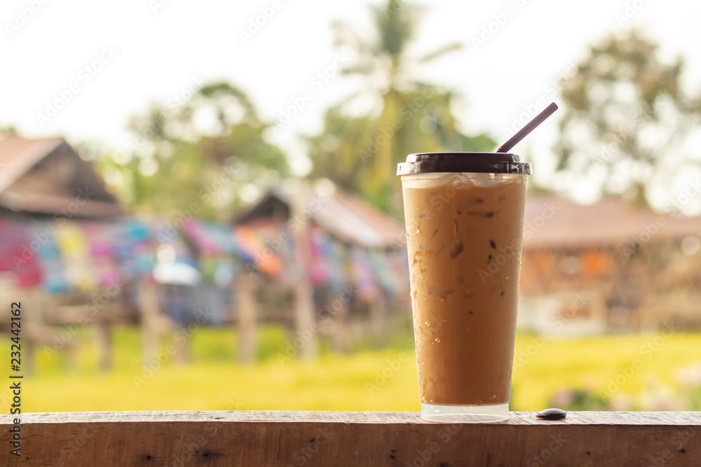 Iced coffee on the wooden floor behind a paddy field and colorful ...