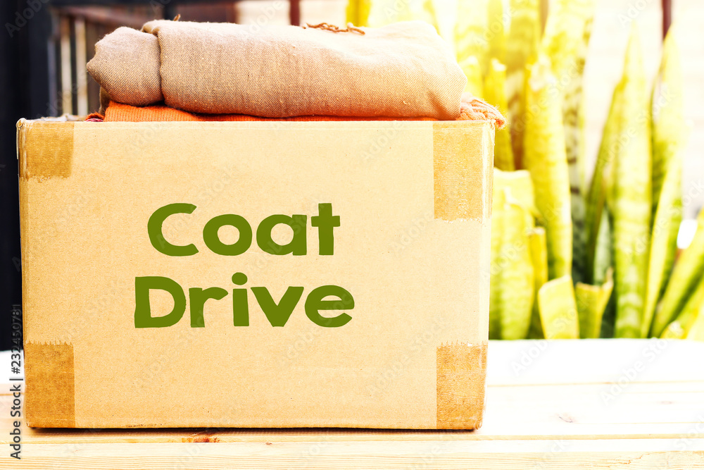 clothes in carton box on wood table for donation, coat drive concept ...