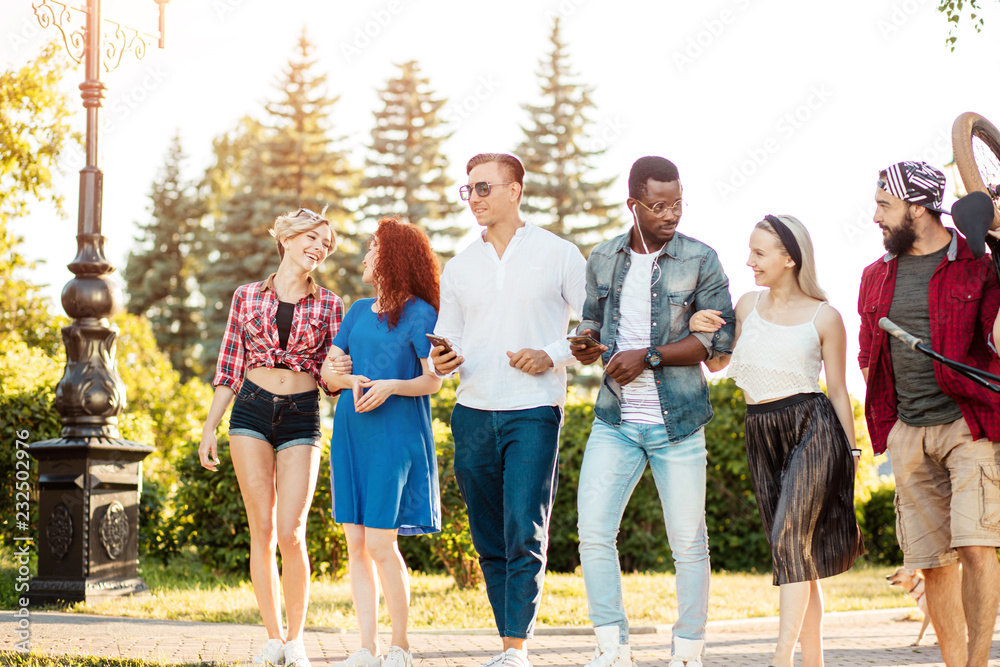 Multi-ethnic group of young cheerful people bonding outdoors, having a ...