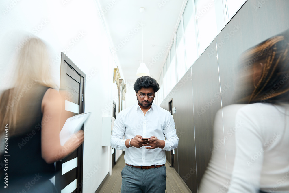 Indian office worker is using smartphone while walking in the office ...
