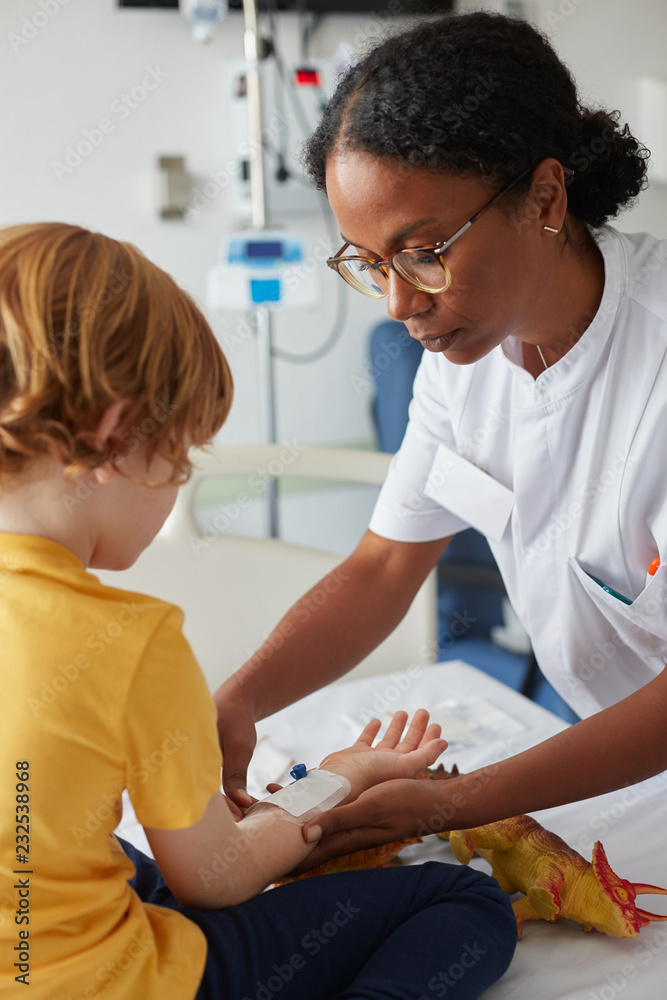 Doctor female giving attention and care to child in a hospital room ...