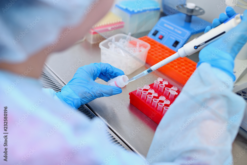Dna test in the lab. a laboratory technician with a dispenser in his ...