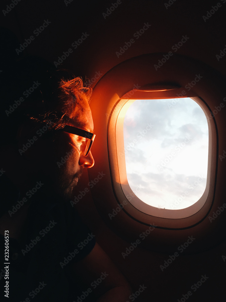 Man looking through plane window Stock Photo | Adobe Stock