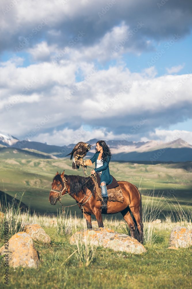 female hunter on a horse with a golden eagle on her arm in beautiful ...