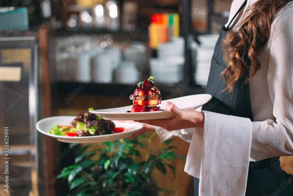 Waiter serving in motion on duty in restaurant. The waiter carries ...