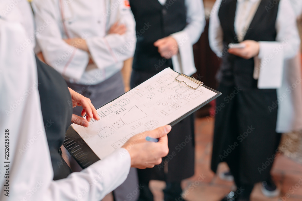 restaurant manager and his staff in kitchen. interacting to head chef ...