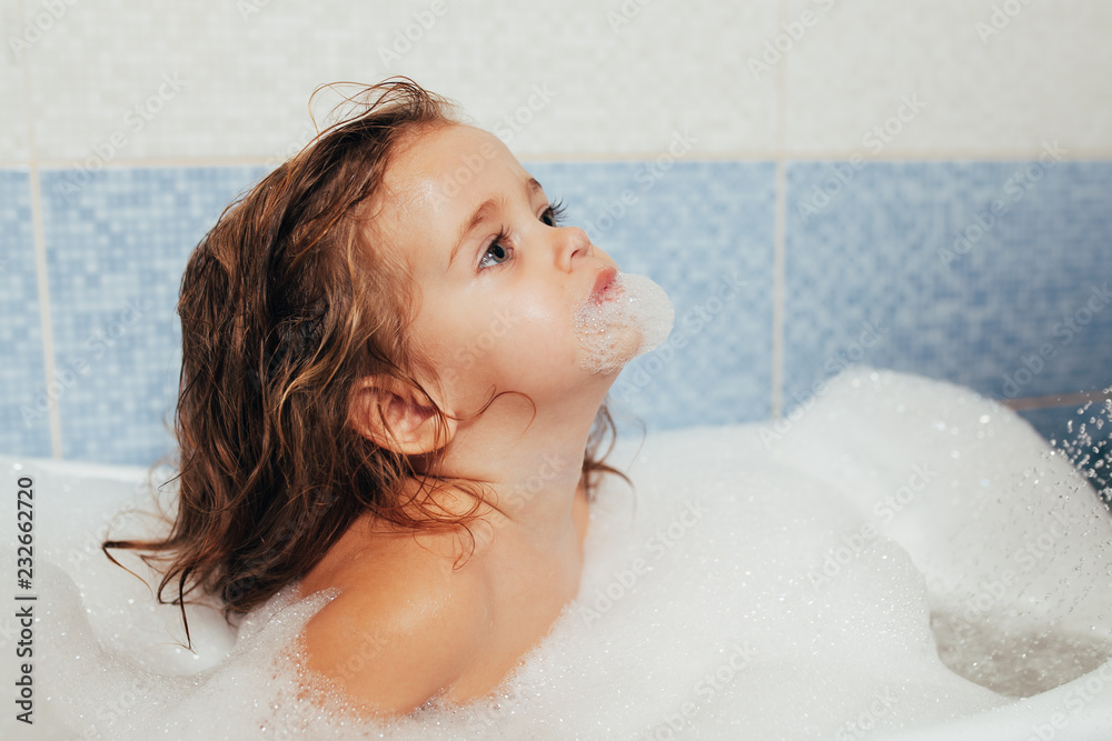Fun cheerful happy toddler baby taking a bath playing with foam bubbles ...