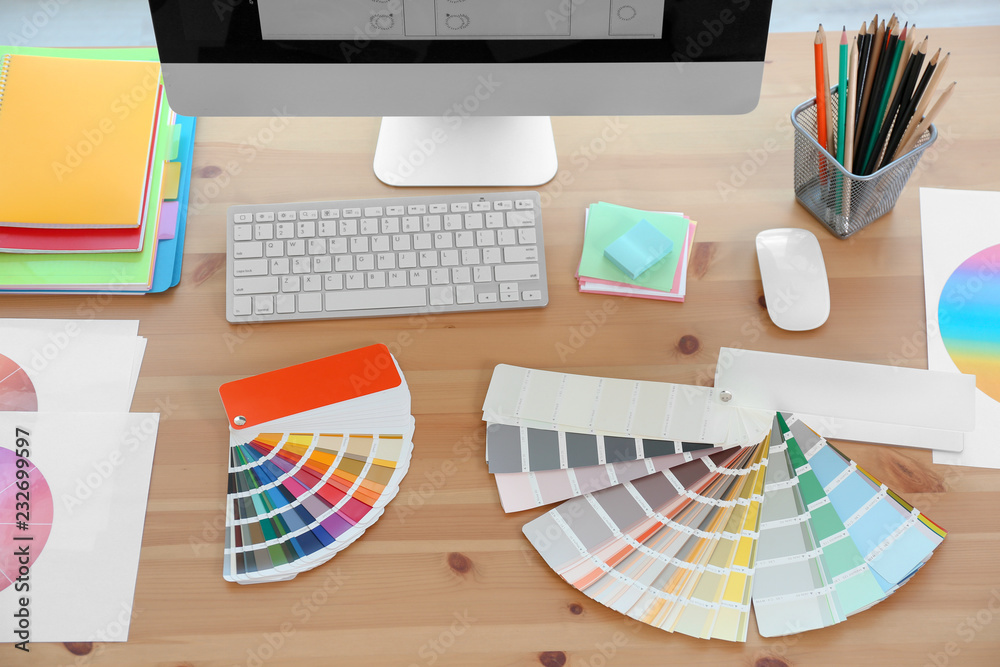 Designer's workplace with computer and paint color palette samples on ...
