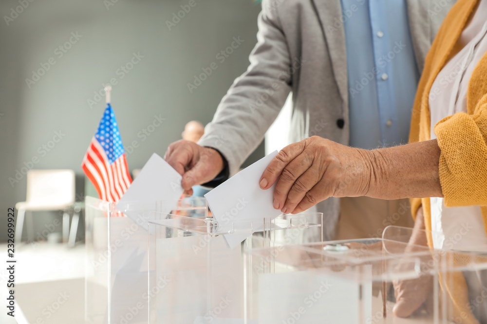 Elderly people putting ballot papers into boxes at polling station ...