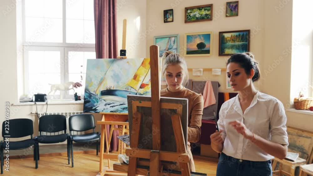 Experienced artist is teaching cute girl student to paint flowers ...