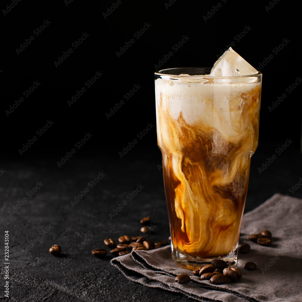 tall glass cold brew coffee with ice and milk on black or dark ...