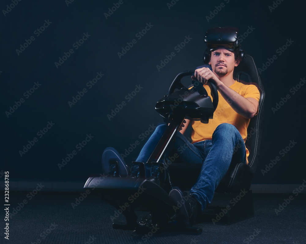 Man dressed in yellow shirt and jeans in VR headset sitting on a car ...