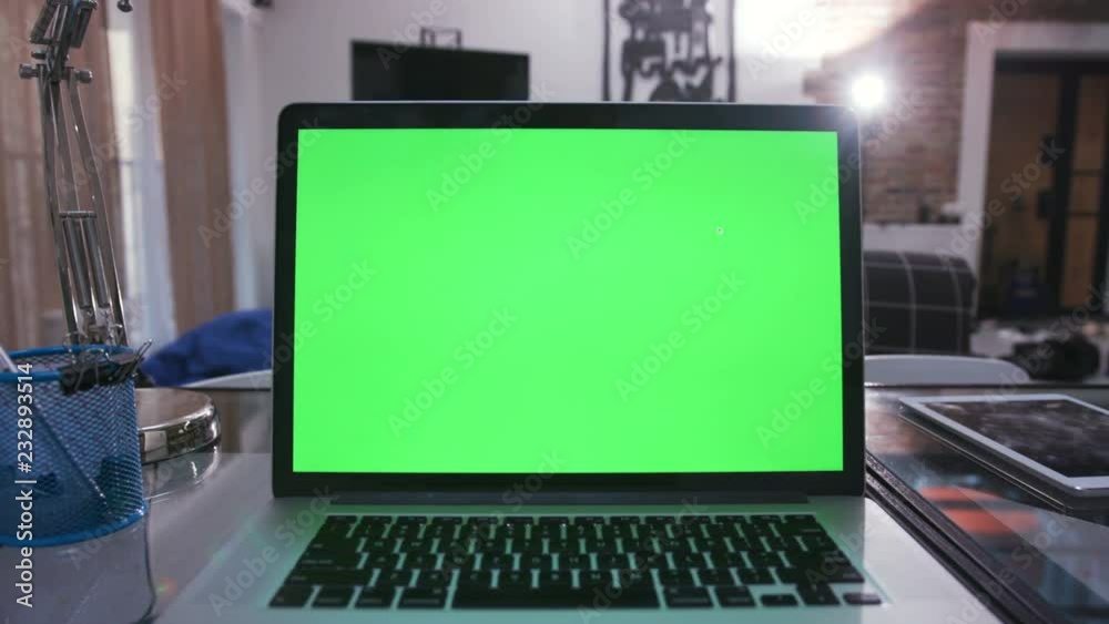 Chrome key green screen. Close-up of screen of silver laptop with black ...