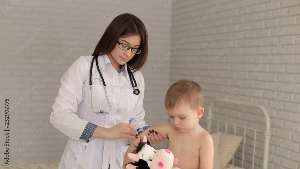 Doctor giving a child an intramuscular injection in arm. Young woman ...
