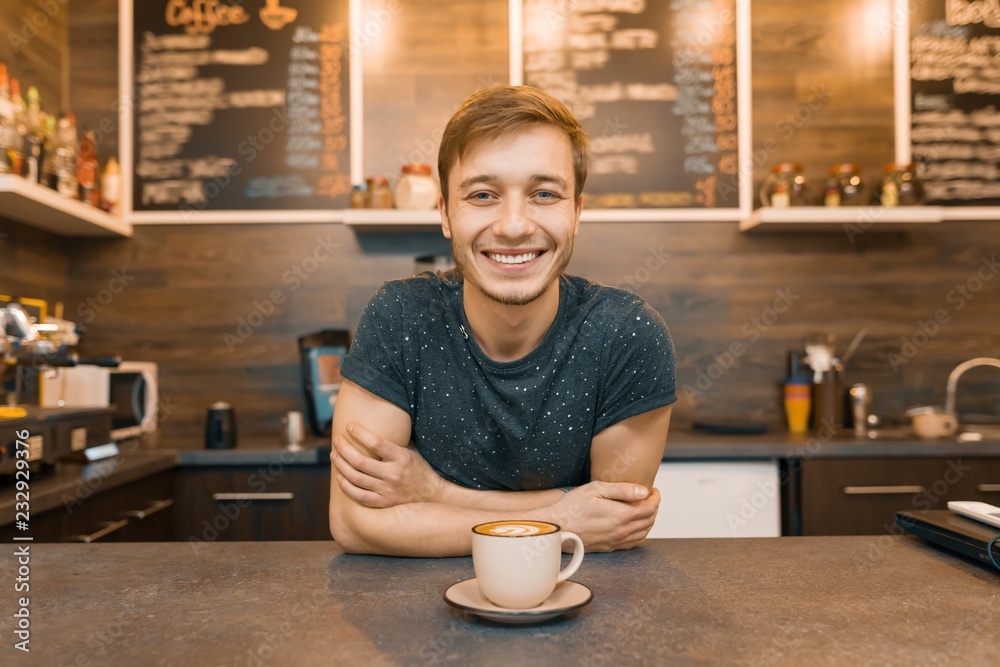 Portrait of young smiling male barista with prepared drink with arms ...