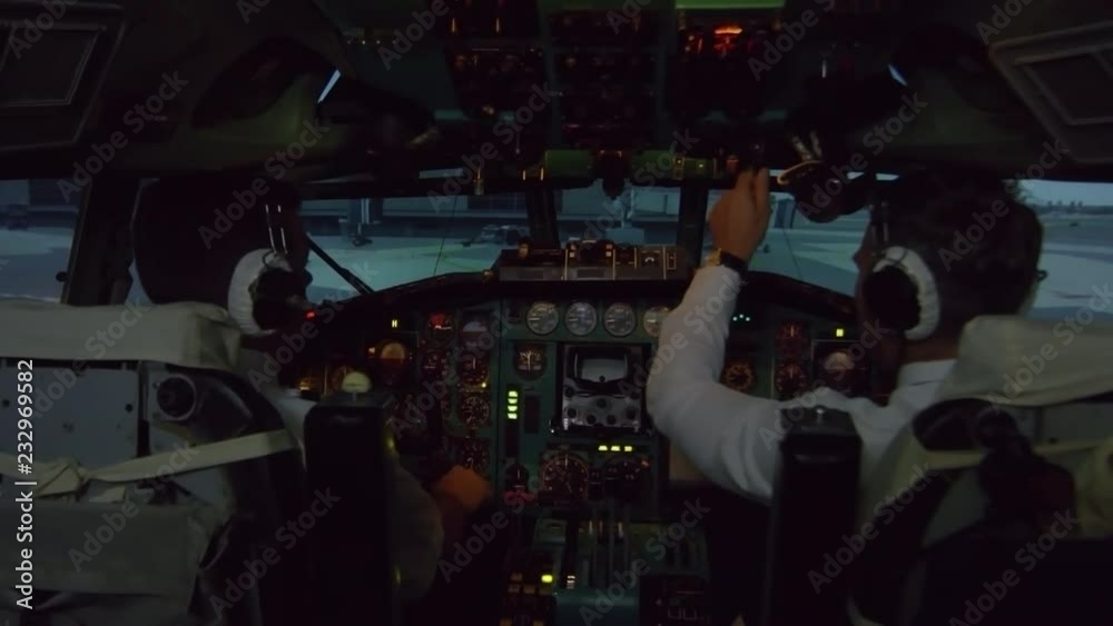 Medium shot from inside of cockpit: professional male pilots in ...