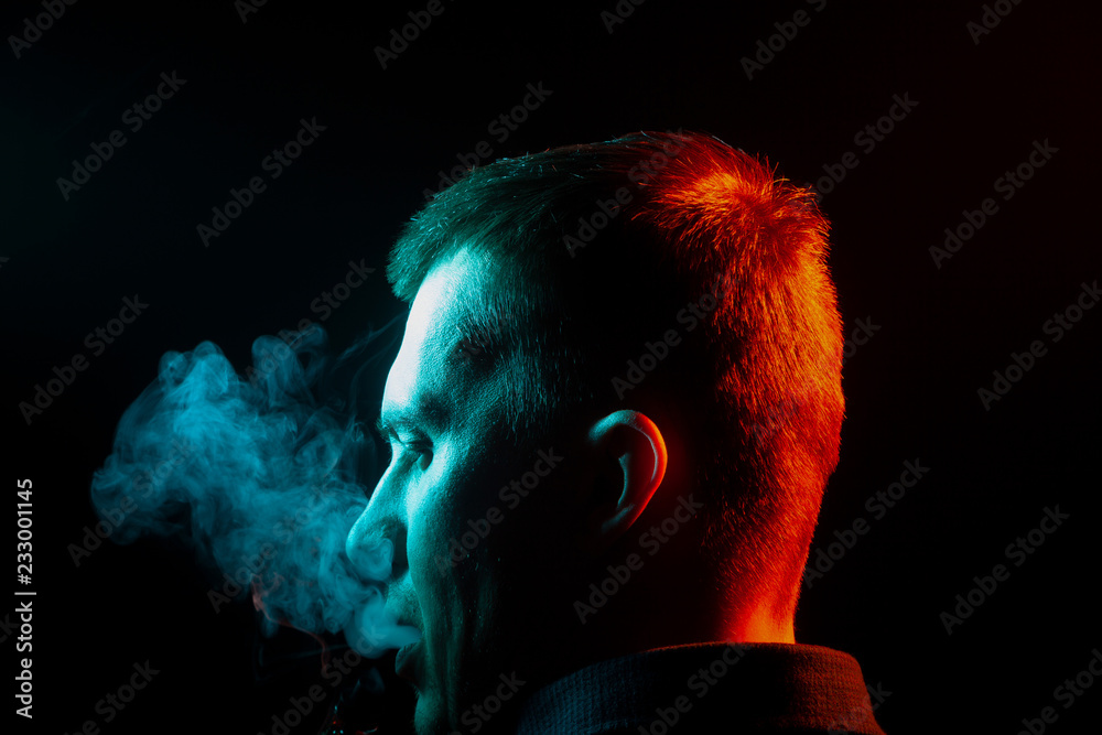 A view from the back of a man’s head around in a shirt smoking a ...