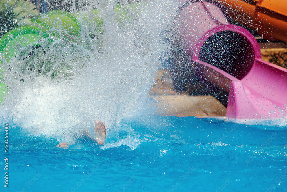 Colorful plastic water slides in waterpark. Water splashes are all over ...