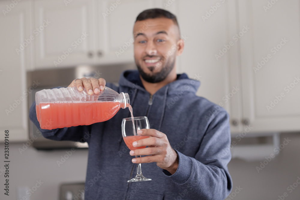 Happy man pouring juice in a glass, Out of focus man pouring juice with ...