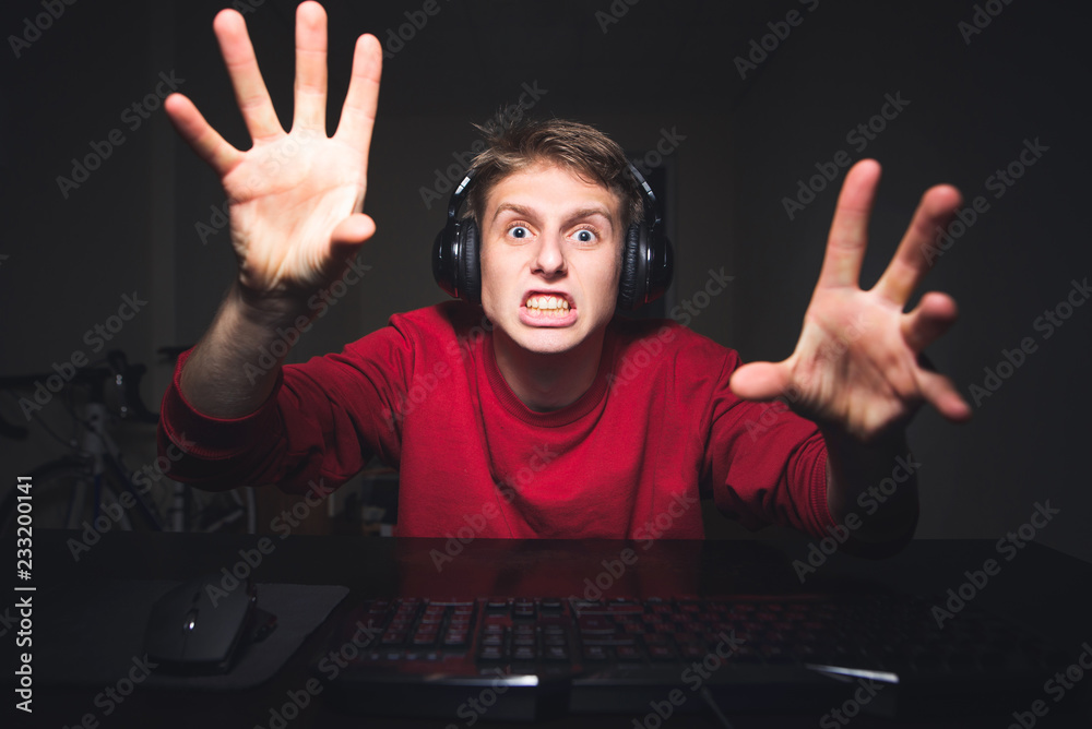 Emotional young gamer plays house games on a computer. Young man plays ...